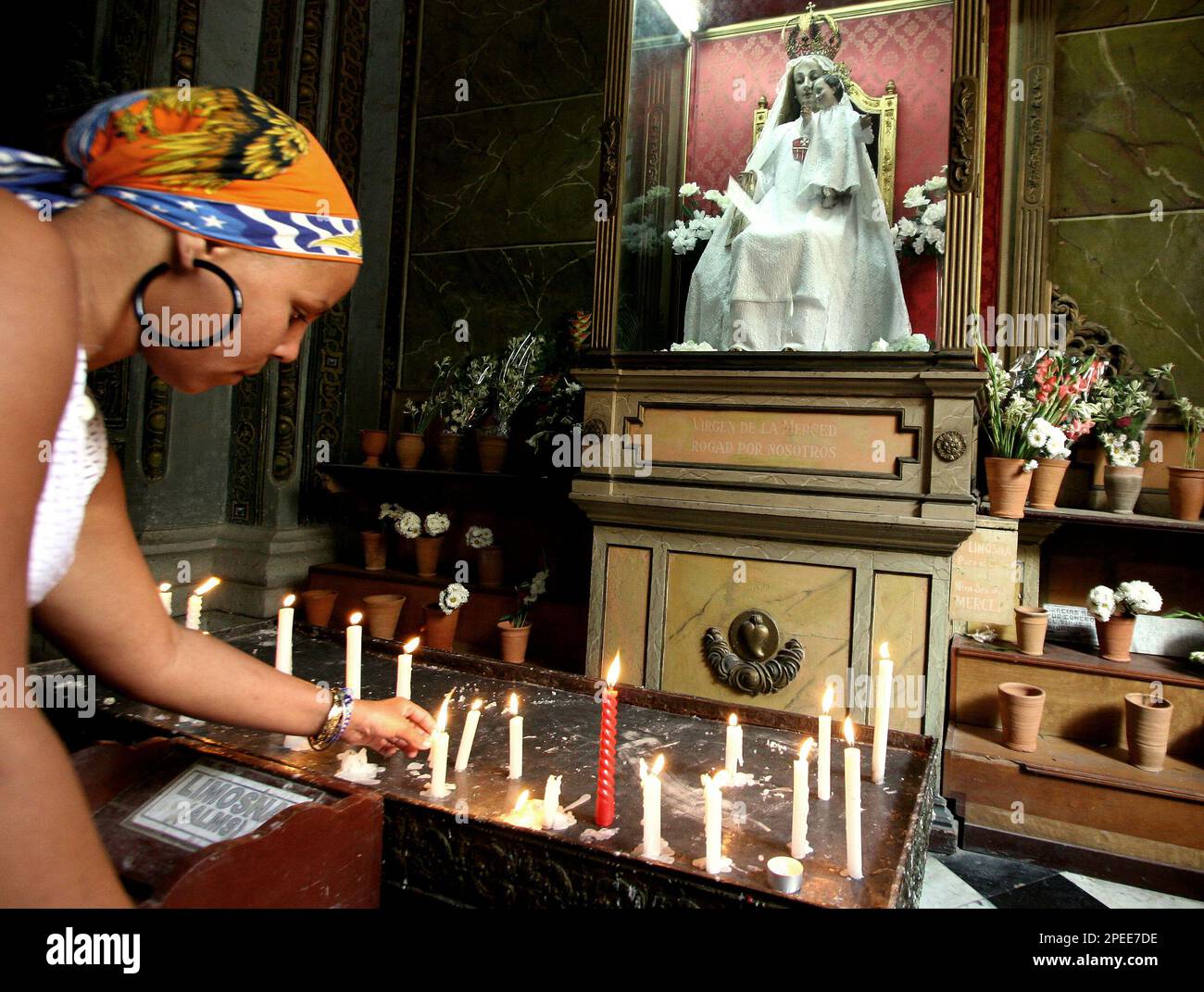 Cuban Martha Garcia places a candle to Our Lady of Mercy, " La Virgen ...