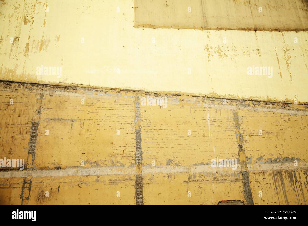 Brick wall of an old house painted yellow and ocher colors. Weathered ...