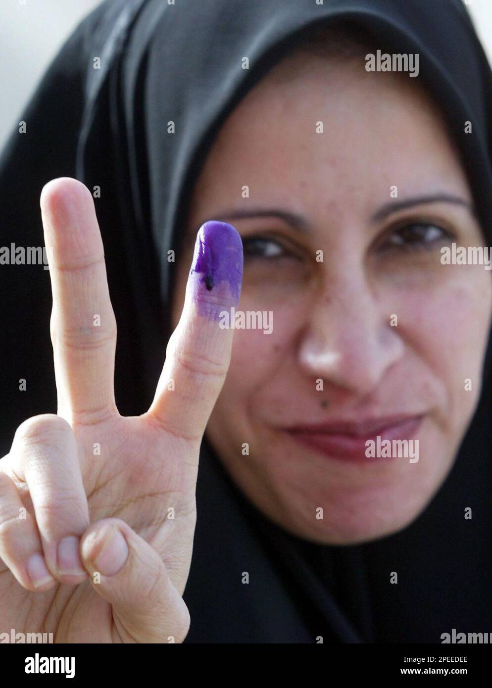 An Iraqi woman holds up her hand, and shows a purple finger, indicating ...