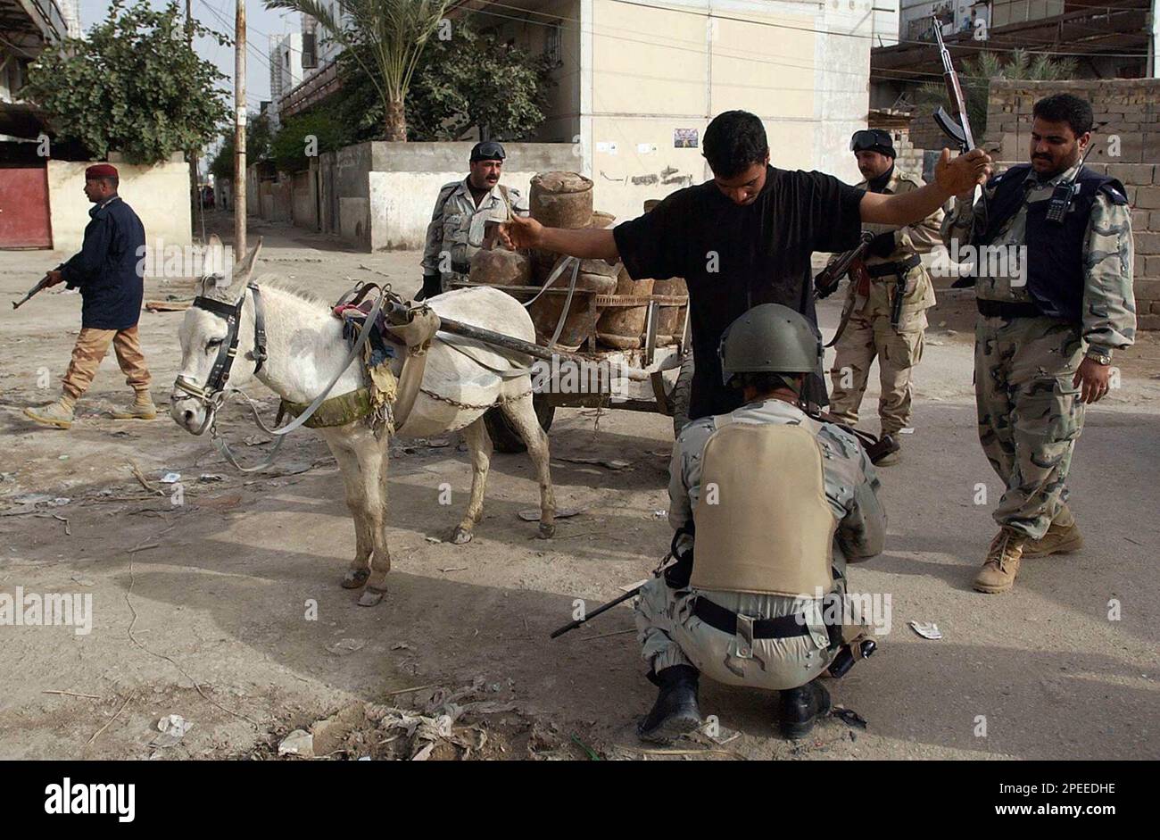 Iraqi soldiers check an Iraqi man arriving with his donkey at a polling ...