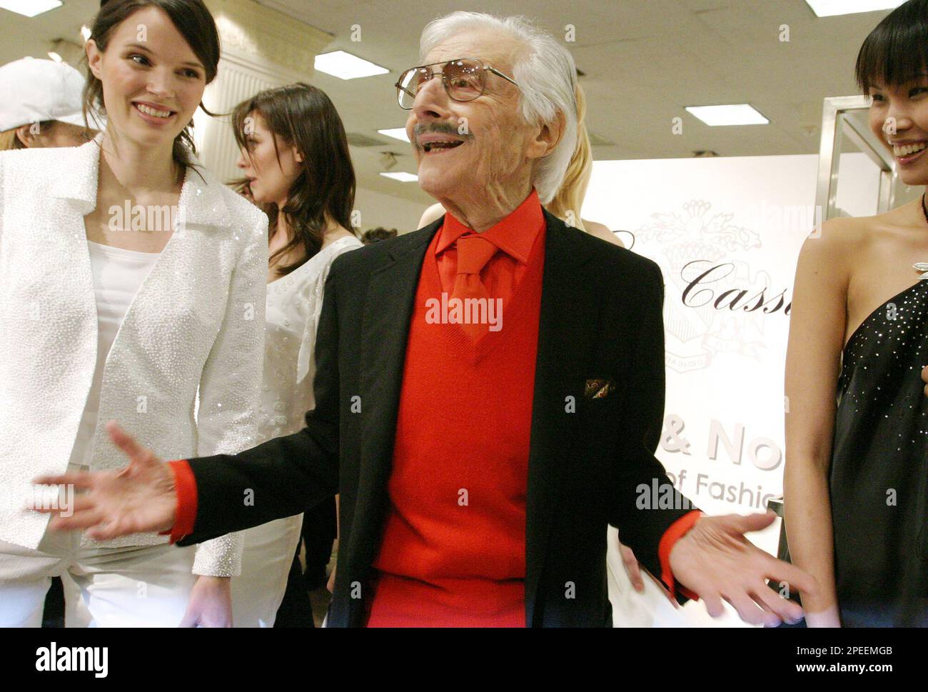 Designer Oleg Cassini, center, jokes around as he poses for photographs ...