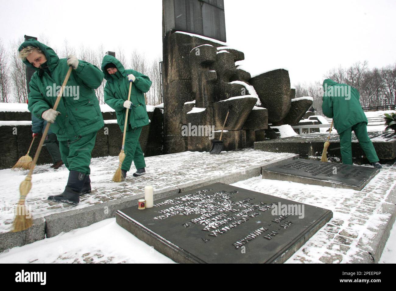 Polish workers wipe off snow from the memorial for the victms of the ...