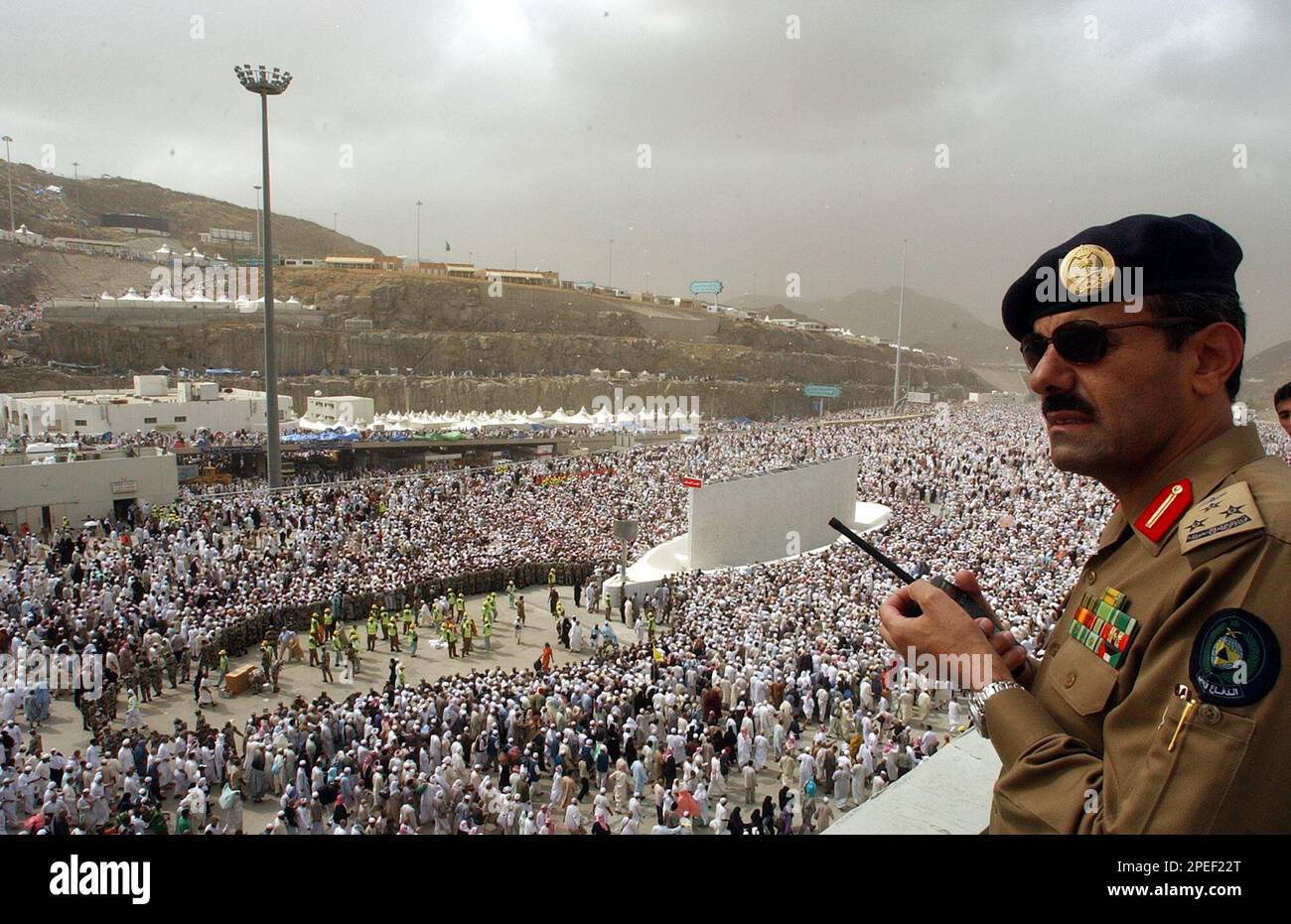 A Saudi police officer stands watching millions of pilgrims crowd to ...