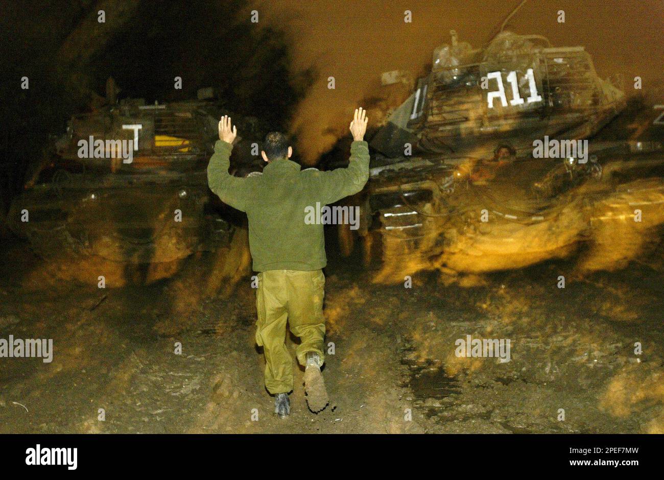 An Israeli soldier directs two tanks as troops gather near Kibbutz ...