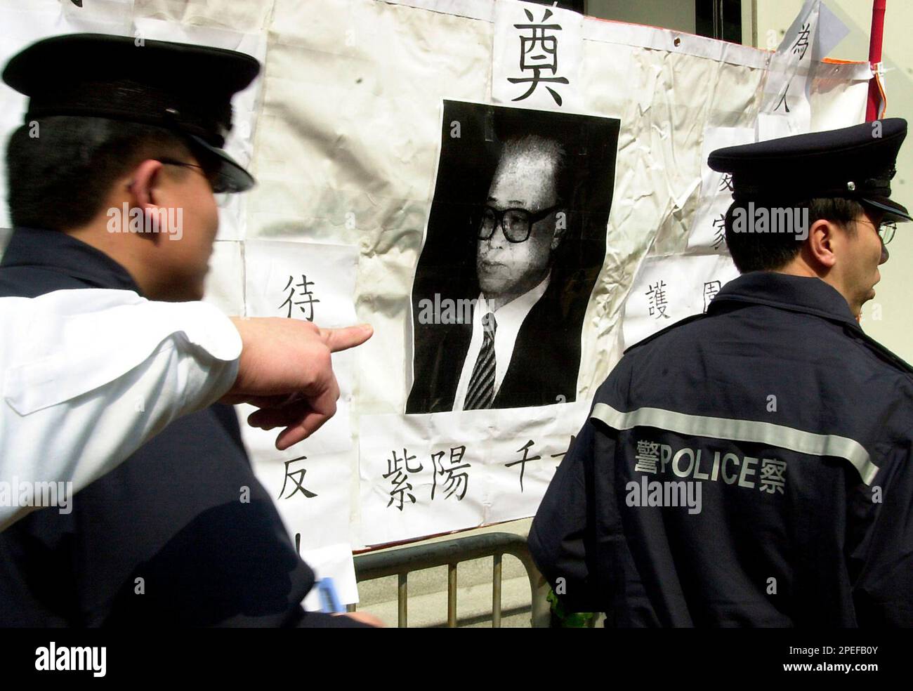 Two police officers move a banner bearing a photo of late Chinese ...