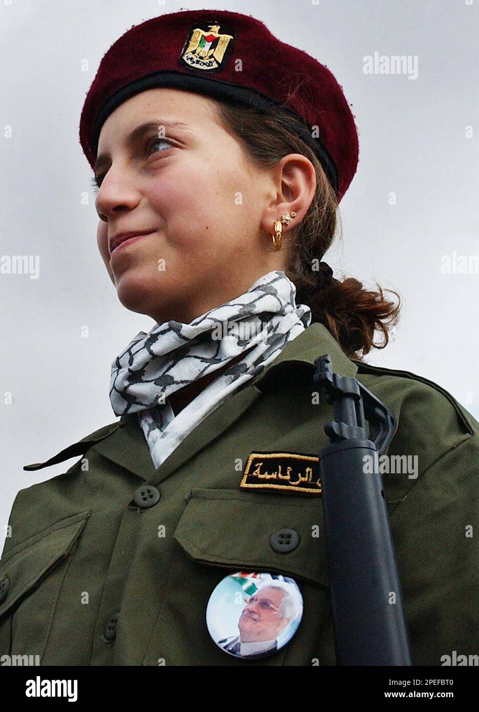 A Palestinian girl wears a uniform with a button bearing a photo of ...