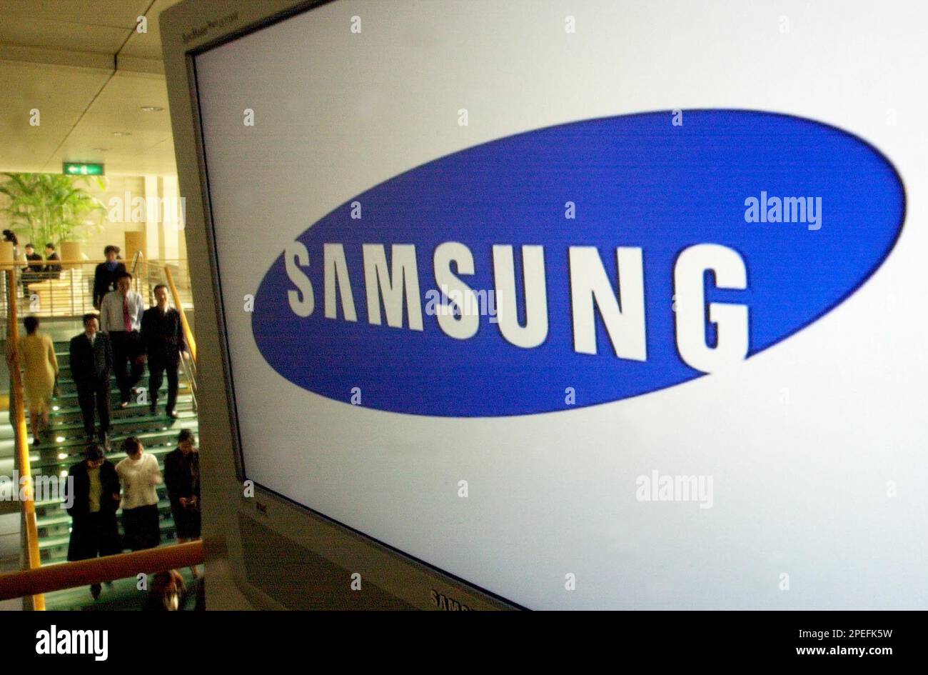 Employees of Samsung Electronics Co. walk by their company logo at the ...
