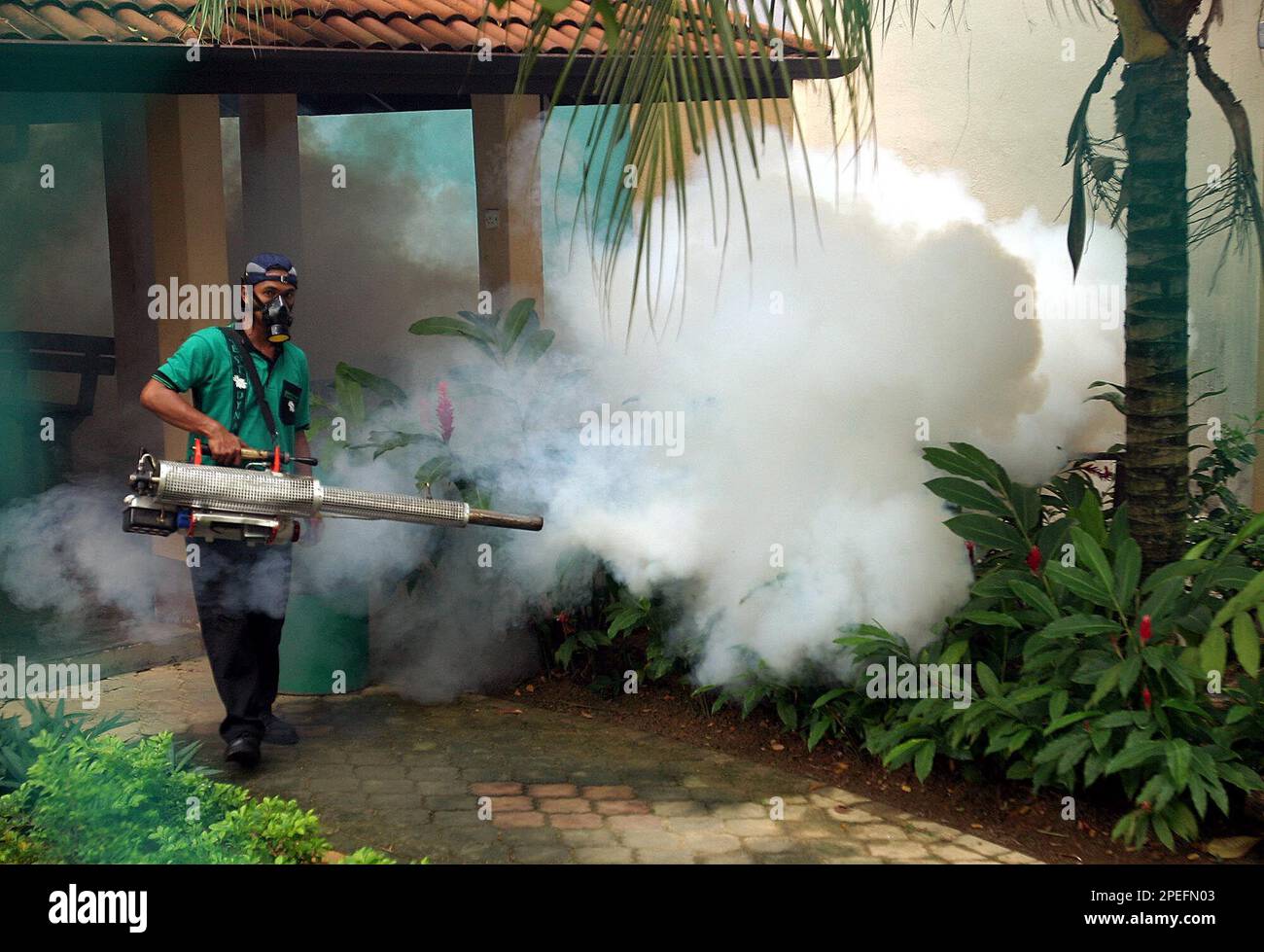 A worker sprays anti-mosquito gas at a garden next to an apartment in ...