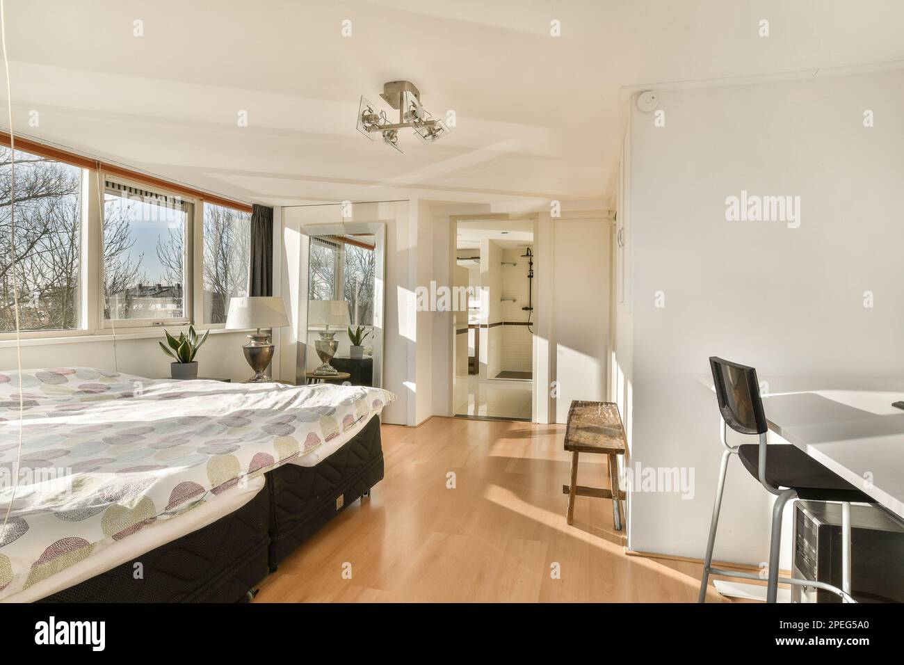 a bedroom with a bed, desk and window overlooking the cityscapet is on ...