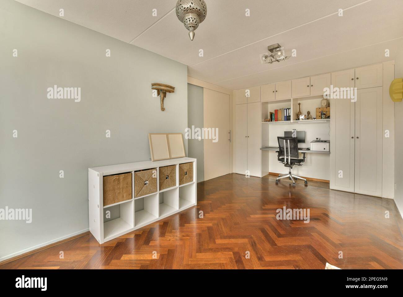 a room with wood floors and white cupboards on the wall, there is a ...