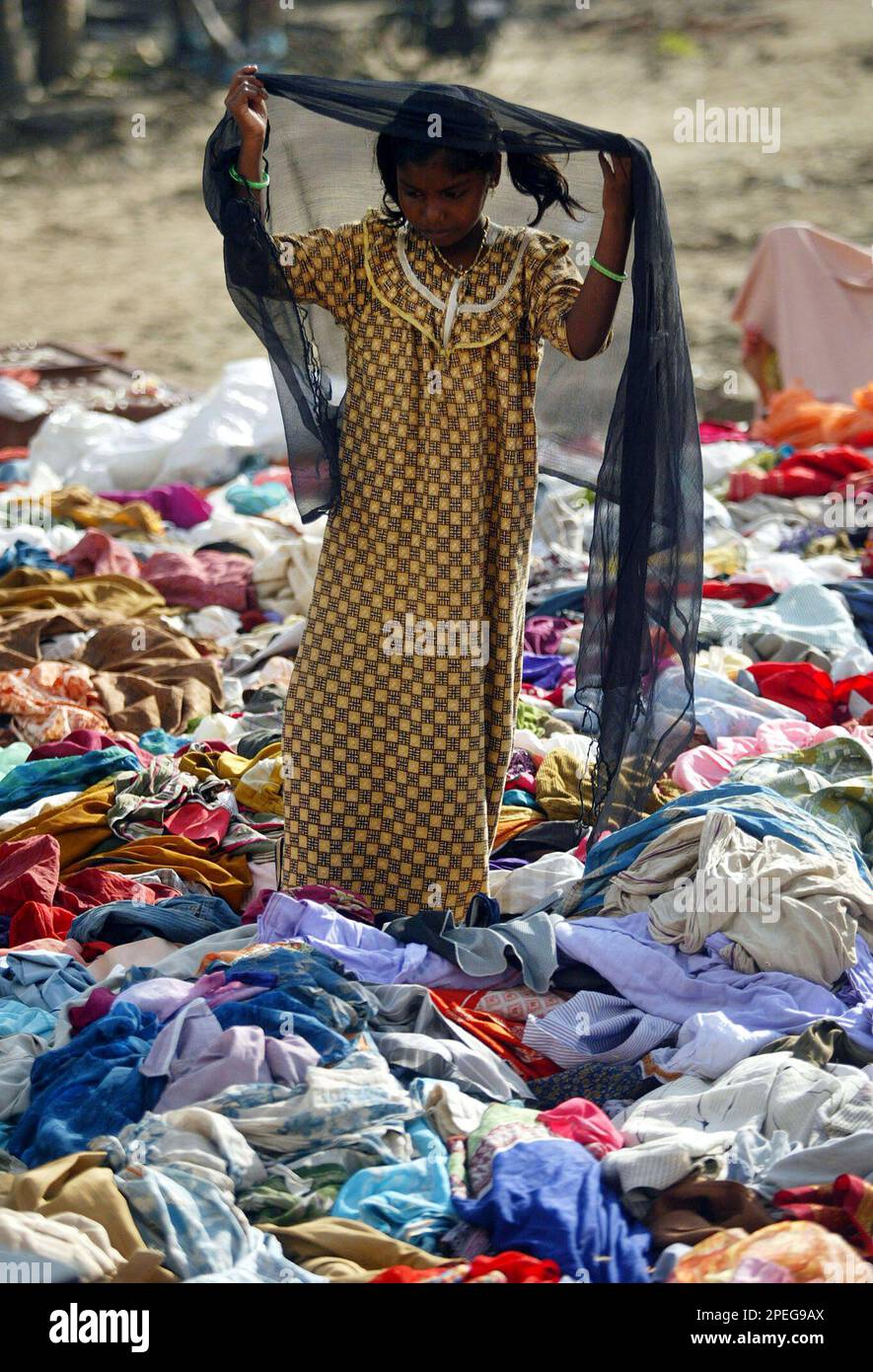 Musma, a girl who was affected by tsunami, tries on a shawl from a pile ...