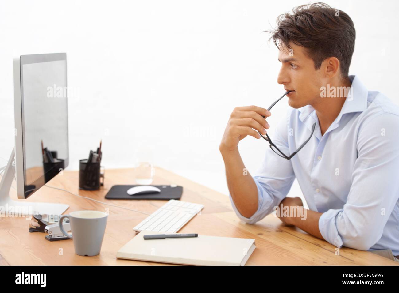 Problem solving is his forte. A young businessman biting his glasses ...