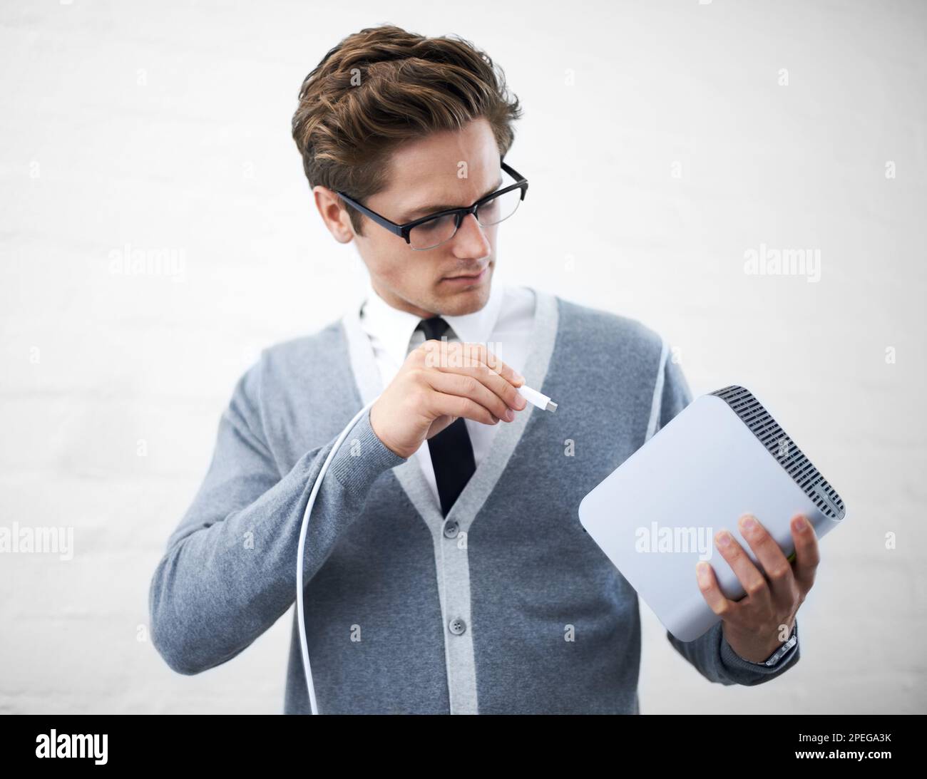 Plugging in to more virtual space. A young nerdy guy plugging in a hard ...