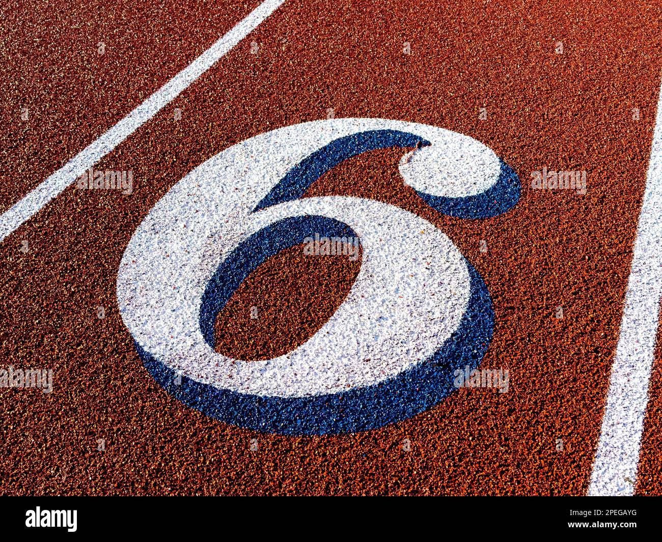 Close up lane number 6 on a new red running track with white lane lines ...