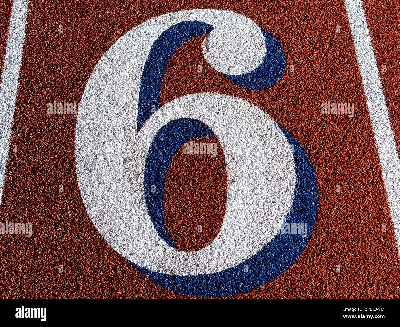 Close up lane number 6 on a new red running track with white lane lines ...