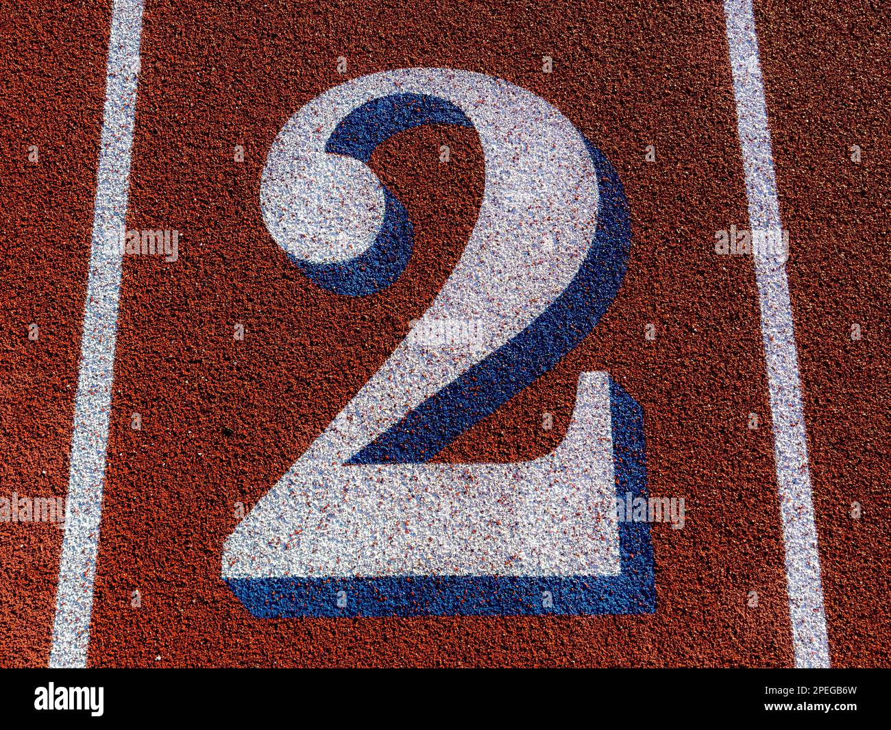 Close up lane number 2 on a new red running track with white lane lines ...