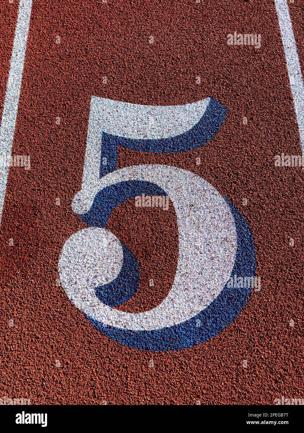 Close up lane number 5 on a new red running track with white lane lines ...