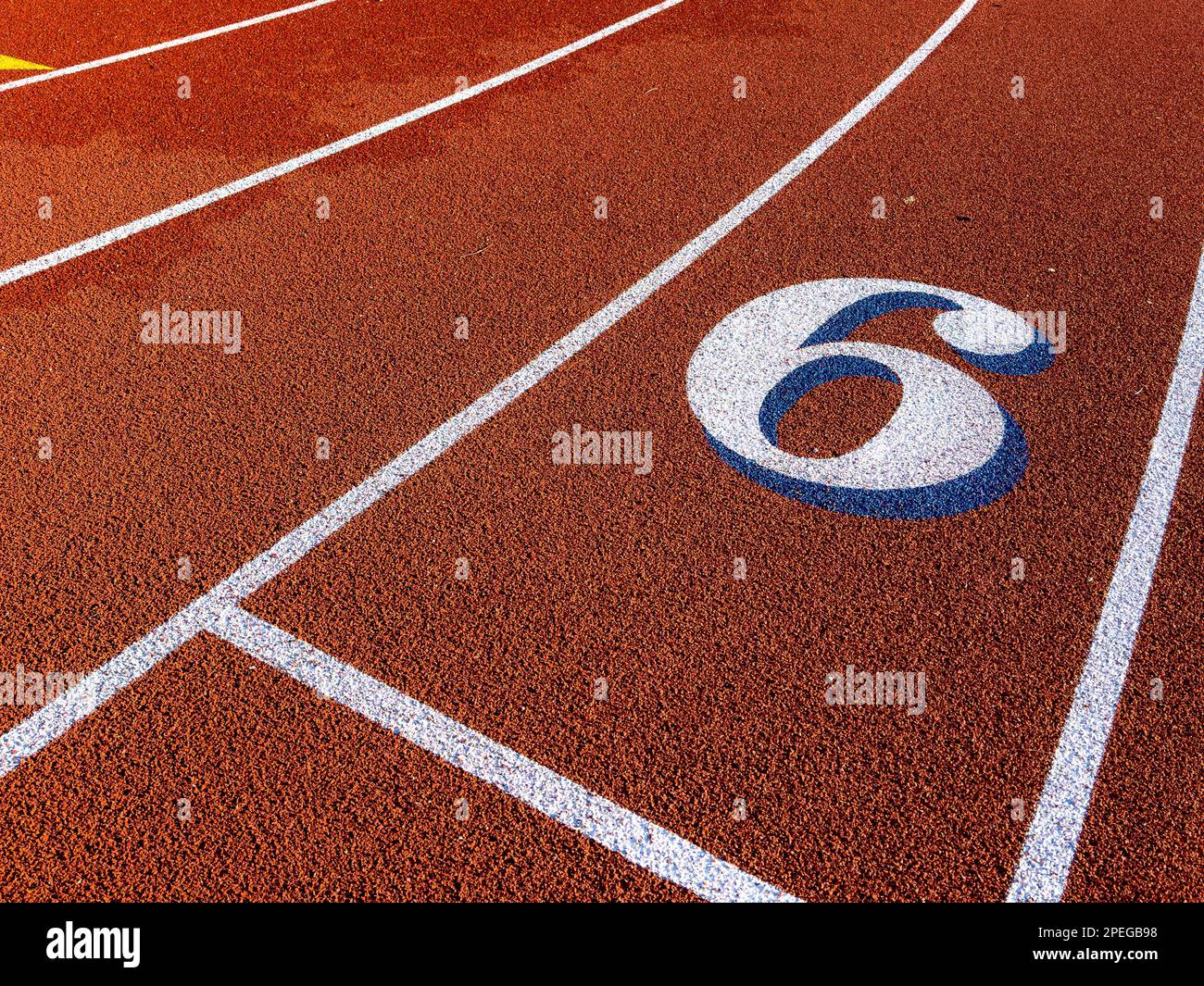 Close up lane number 6 on a new red running track with white lane lines ...