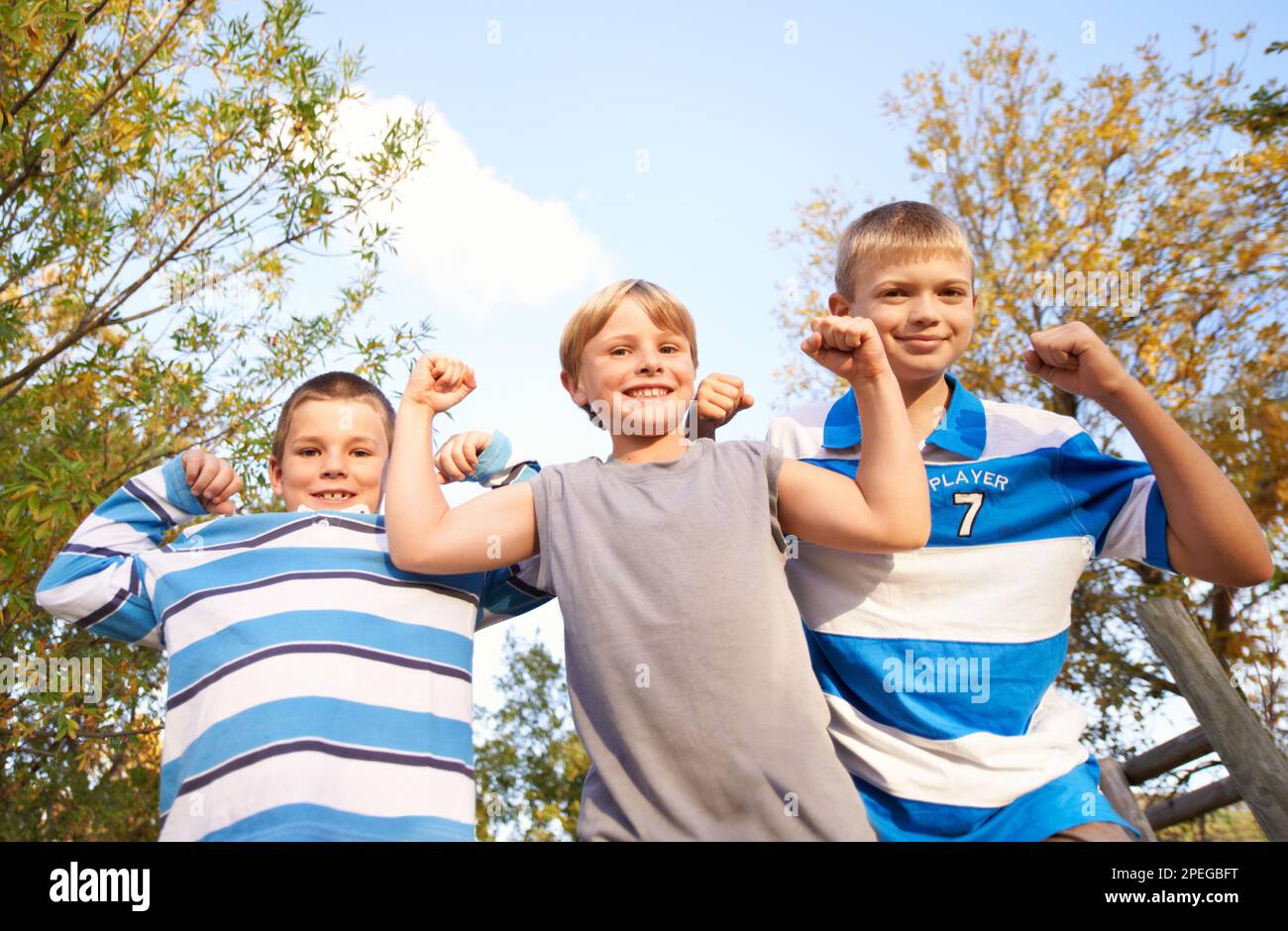 Building muscle by being kids. three young boys flexing their muscles ...