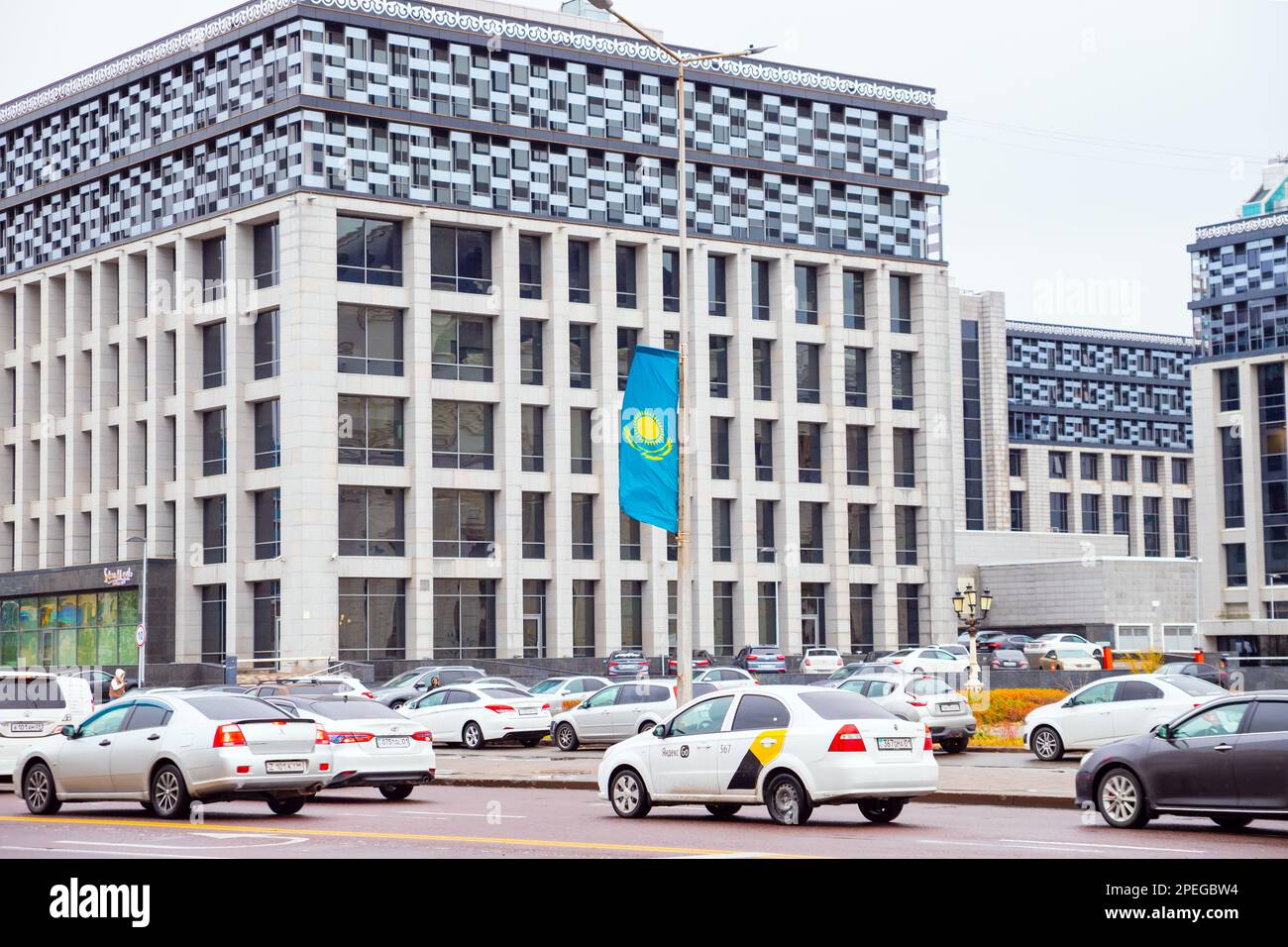 modern building, vertical Kazakhstan flag, highway, cars a lot. traffic ...