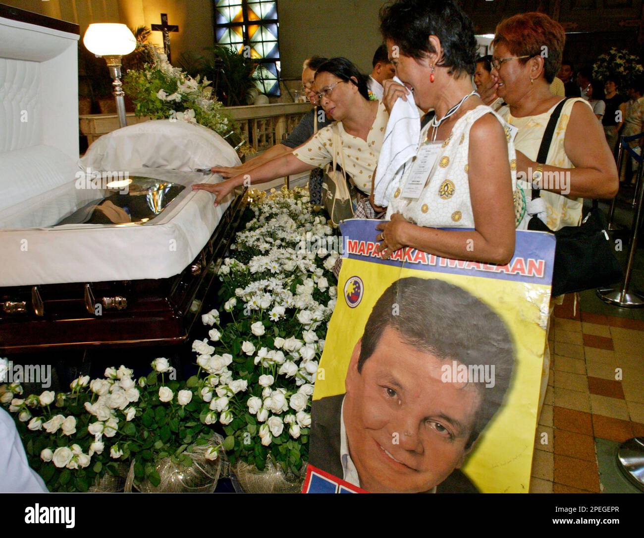 Supporters of former Presidential candidate Fernando Poe Jr., some carrying his portrait, mourn ...