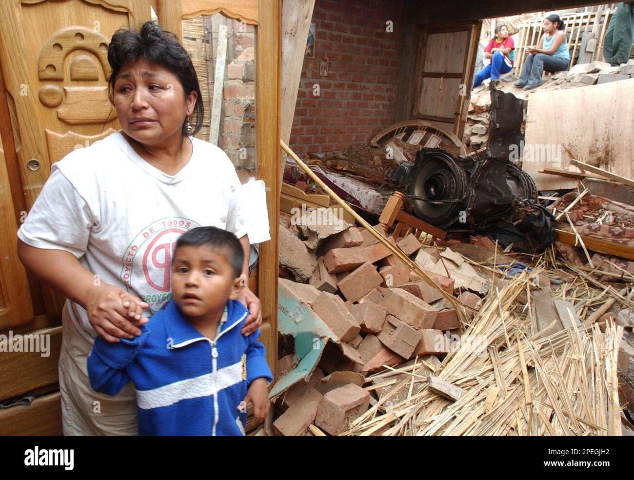 Nelly Azabache, with her son Aldair, 4, cries as she views her home ...