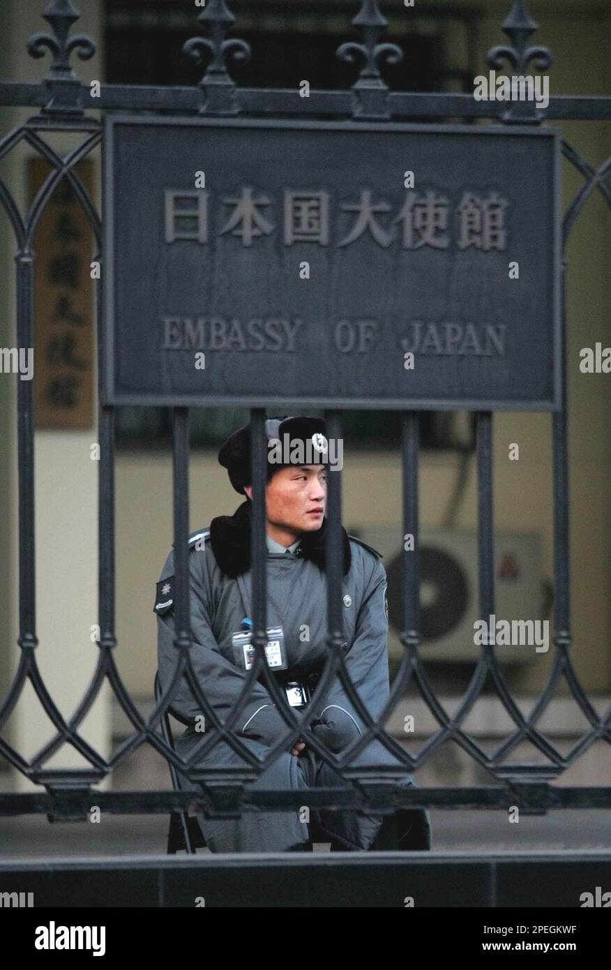 A Chinese security guard sits behind the fence of the Japanese Embassy ...
