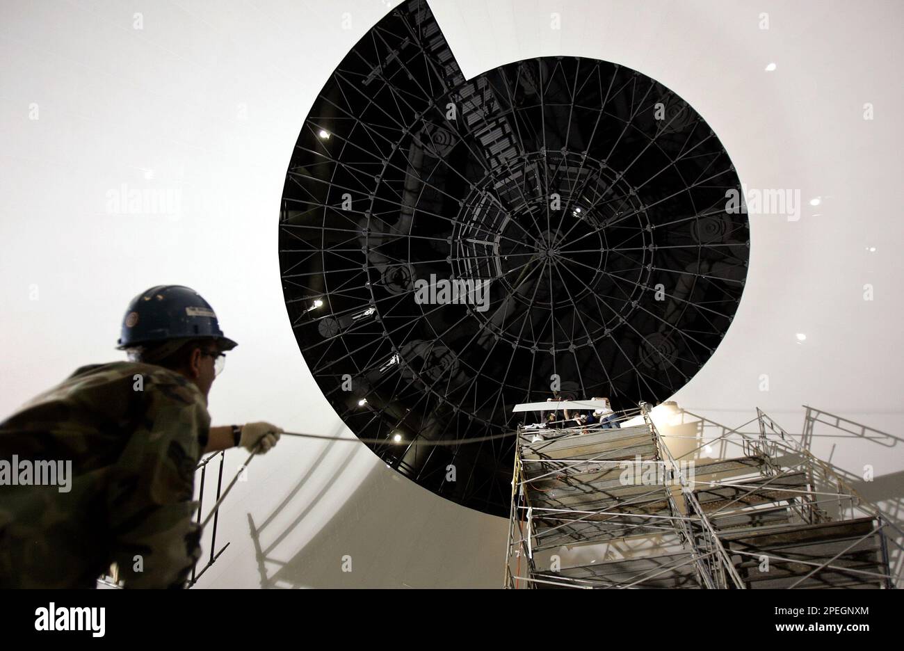 A worker raises a perforated aluminum panel to complete the ...