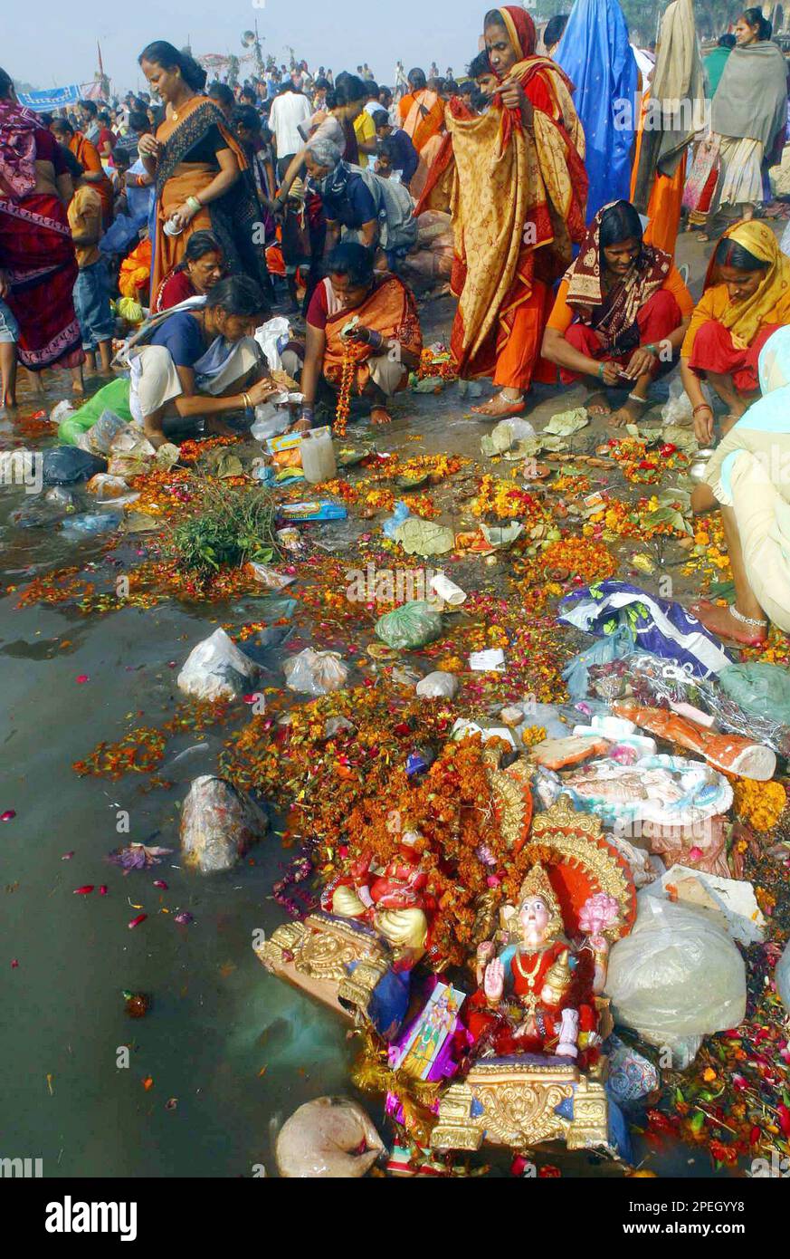 Hindu devotees pray in the river Ganges amid flowers, dirt and broken ...