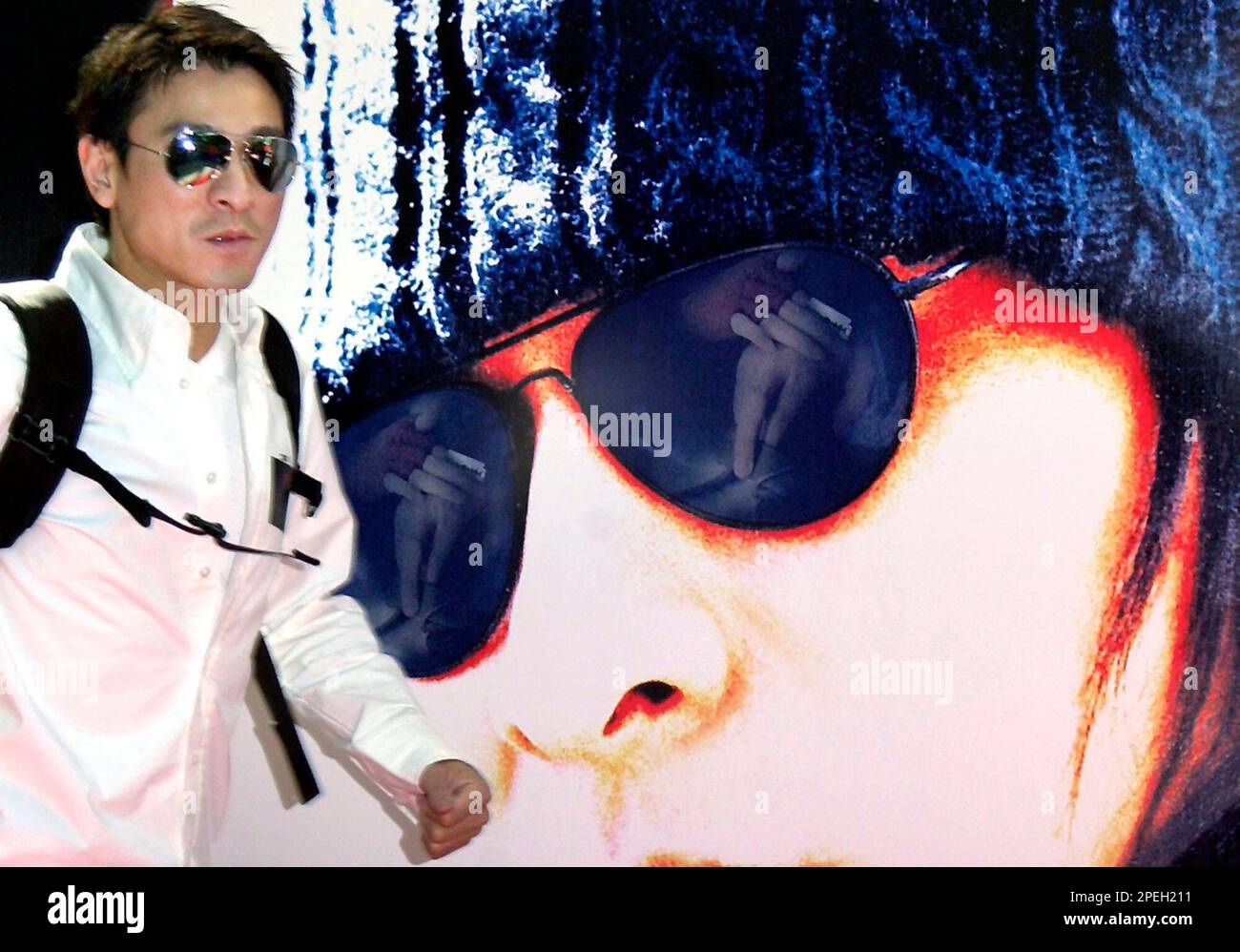 Hong Kong actor-singer Andy Lau walks by a poster bearing his likeness ...
