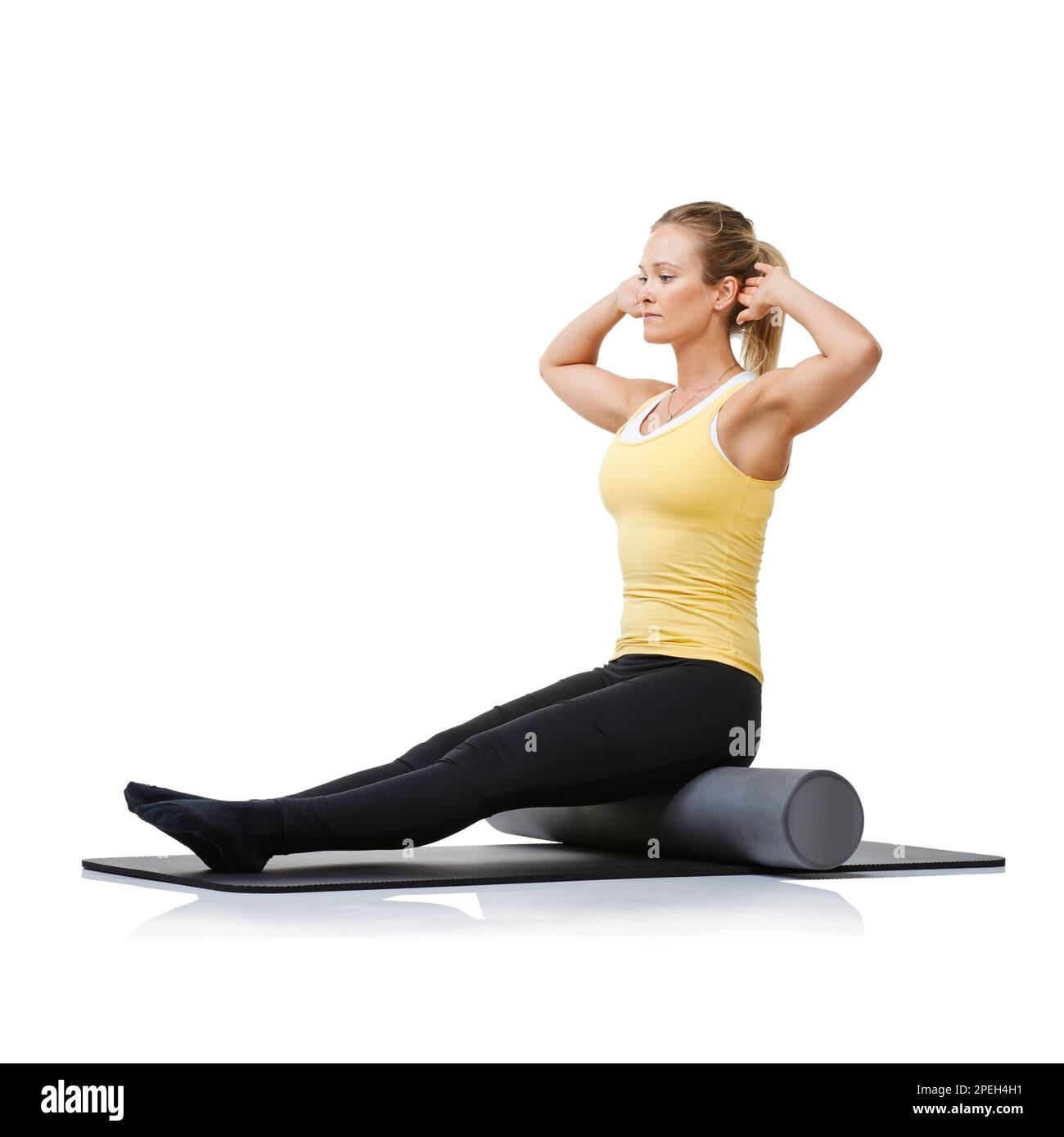 Tensing her stomach muscles. A young woman sitting on a foam roller ...