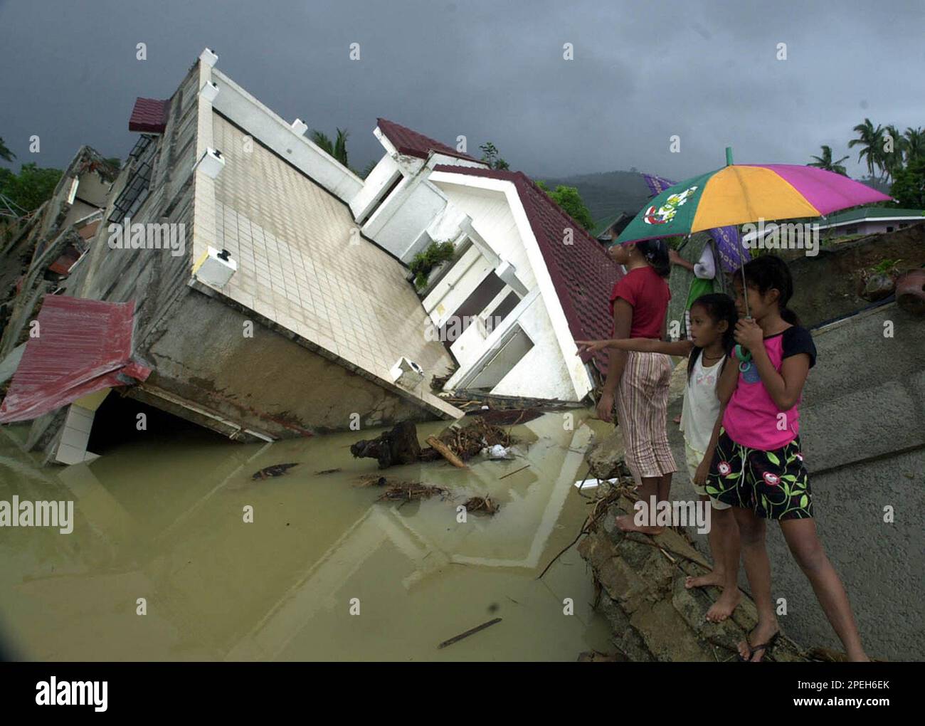 A group of girls watch the destroyed three-storey concrete house Monday ...
