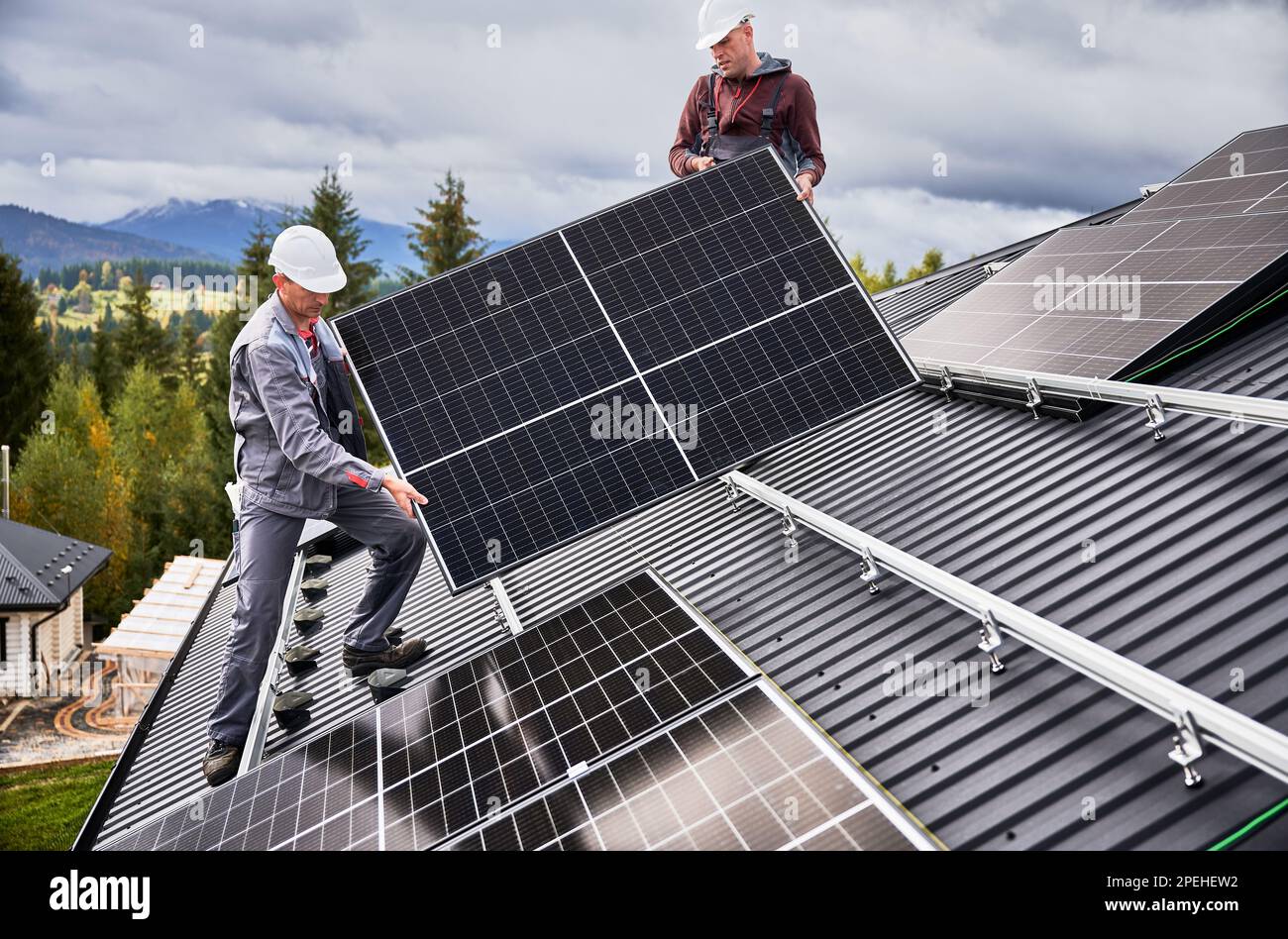 Engineers building solar panel system on roof of house. Men workers in ...