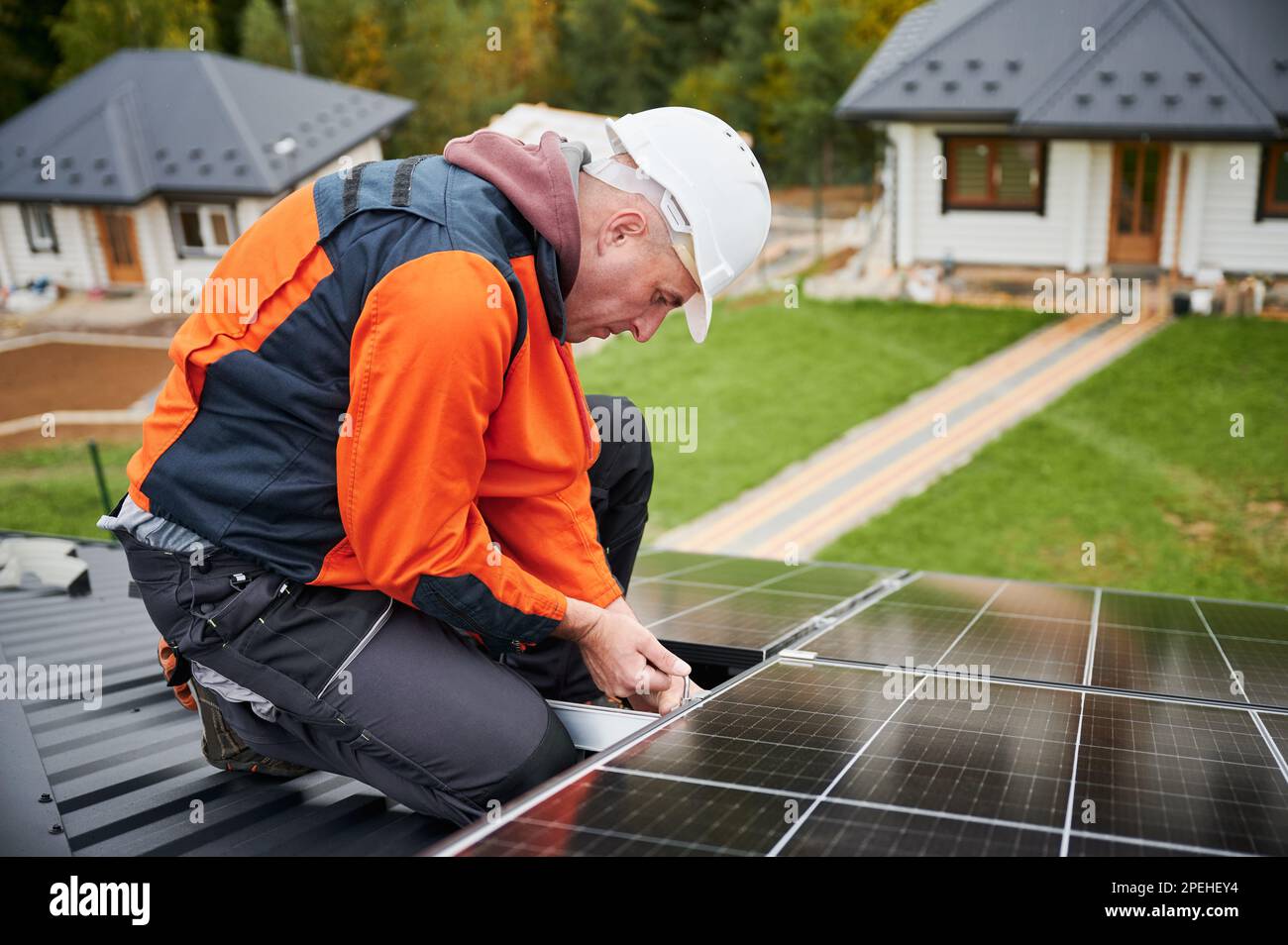 Man electrician mounting photovoltaic solar panels on roof of house ...