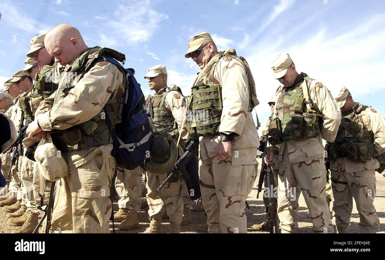 Soldiers bow their heads in prayer before loading the buses that will ...