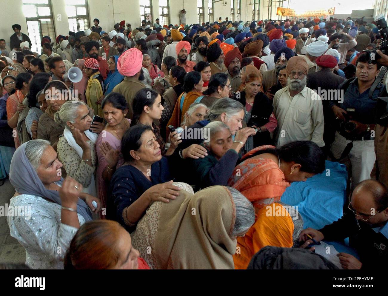 Indian Sikh pilgrims stand at Pakistani immigration counters for ...