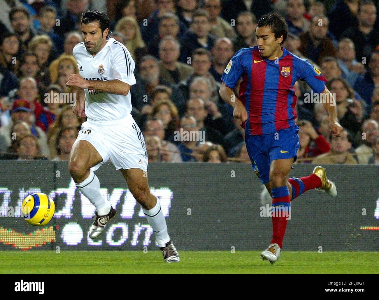 Real Madrid player Luis Figo, left, is followed by FC Barcelona's ...