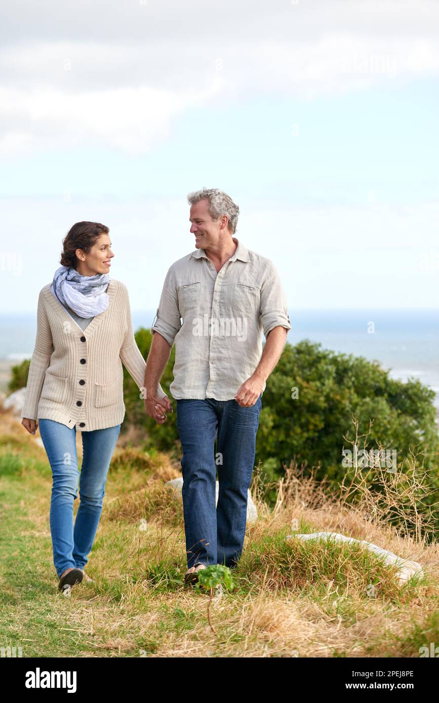 Having a leisurely stroll. A couple holding hands walking along the ...