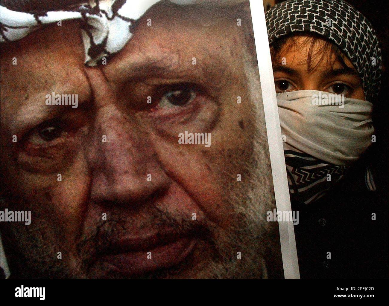 A boy carries a banner with a picture of Palestinian leader Yasser ...