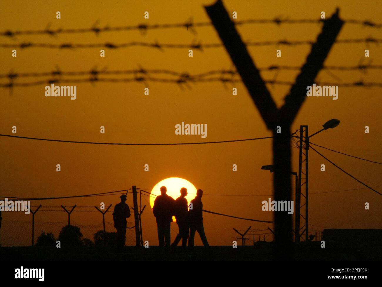 The sun sets as Palestinian security officers walk inside the barbed ...