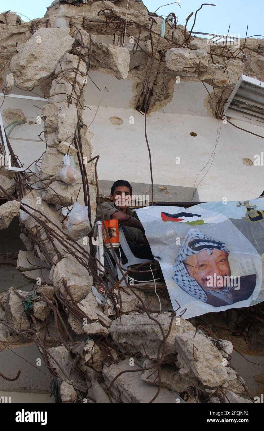 A security guard sits next to Palestinian leader Yasser Arafat's poster ...