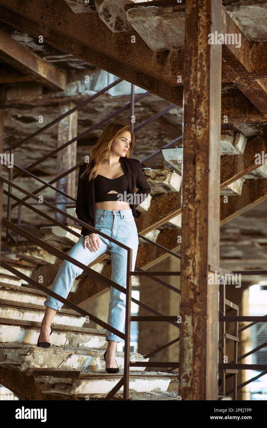 Beautiful serious woman standing inside a derelict building looking ...