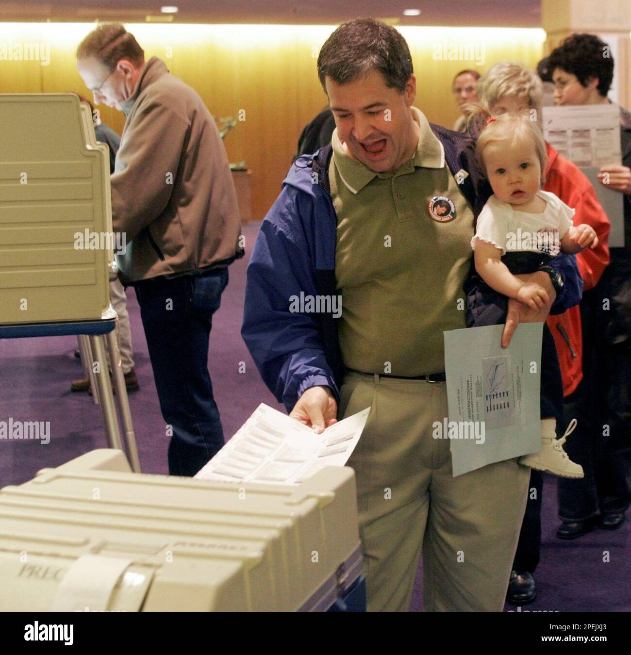 Shawn Nolan casts his ballot while holding his one-year-old daughter ...