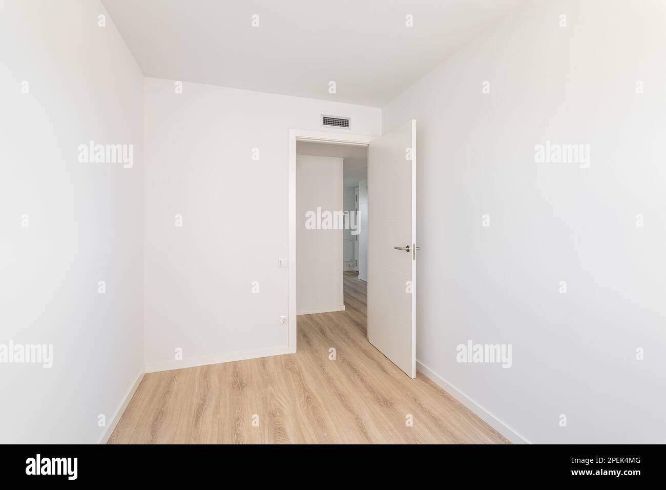 Empty white unfurnished room with wooden laminate flooring, ventilation ...
