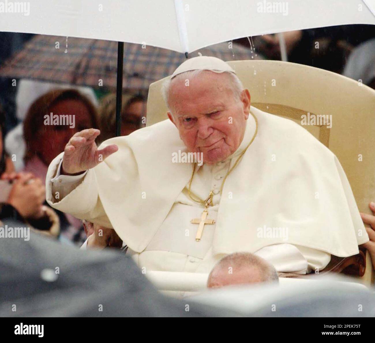 Pope John Paul II, sheltering under a white umbrella, greets the ...