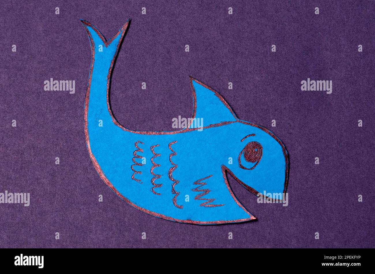 Blue april fool fish cut out of colored paper on a purple background ...
