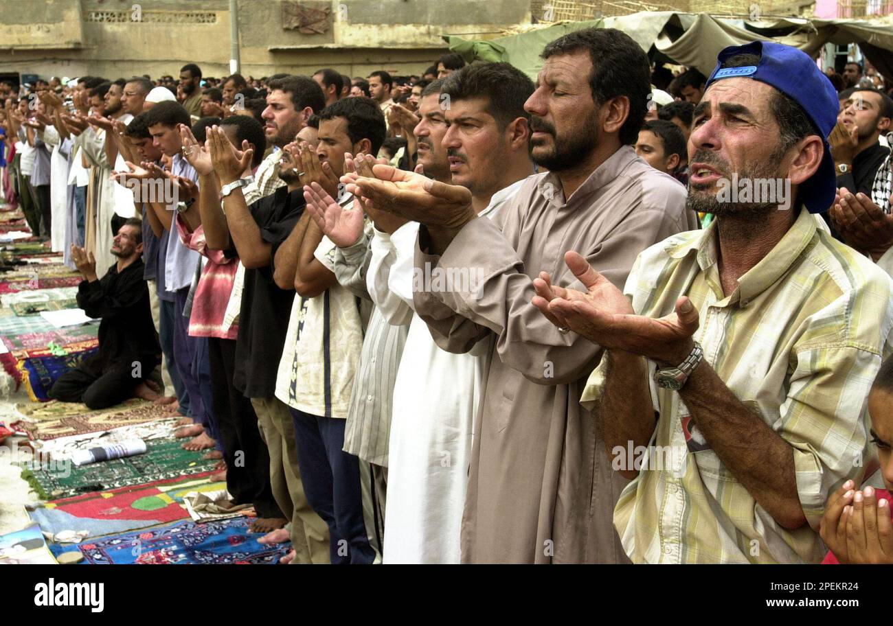 Iraqi men pray as they attend Friday prayers in the yard of a mosque in ...