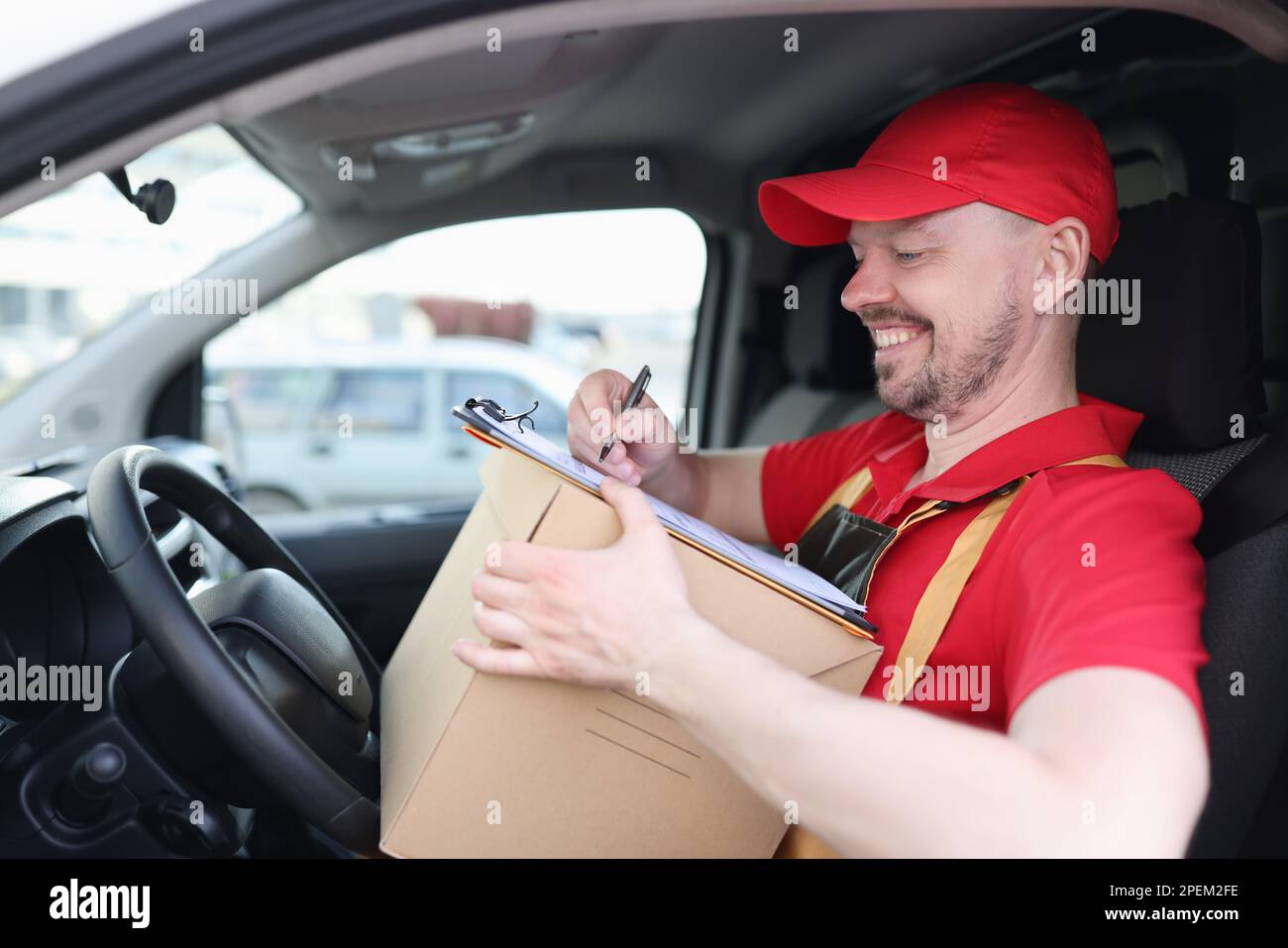 Happy delivery man with cardboard box checklist in van Stock Photo - Alamy