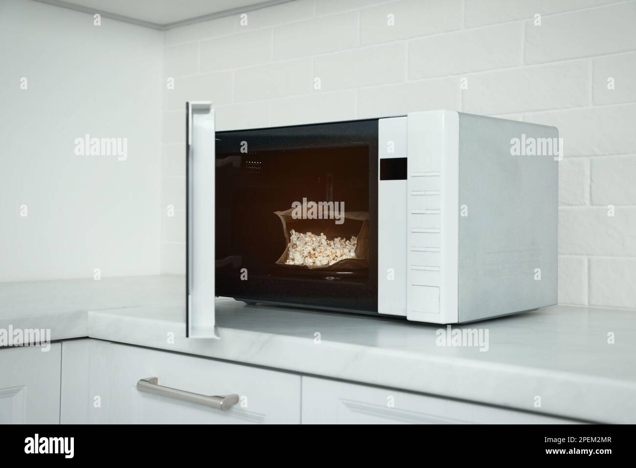 Open microwave oven with fresh popcorn on countertop in kitchen Stock ...