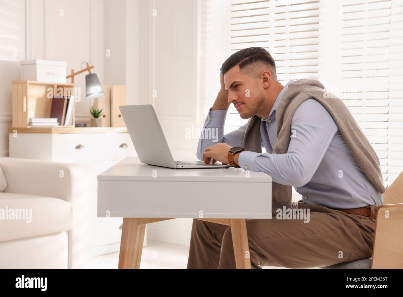 Man with poor posture using laptop at table indoors Stock Photo - Alamy